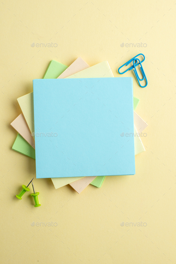 Vertical view of stacked coloured note cubes paper clips drawing pins ...