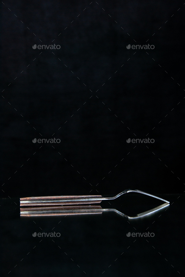 Vertical view of elegant shiny metal fork put upside down on black ...