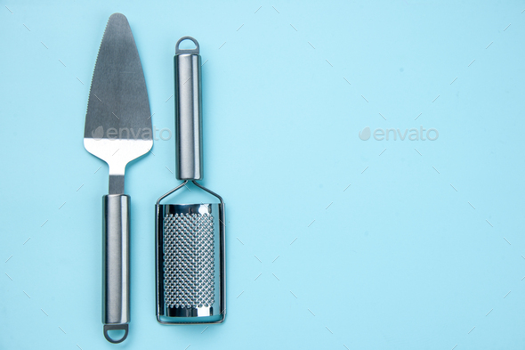 Top view of two stainless kitchen tools on the right side on blue wave ...