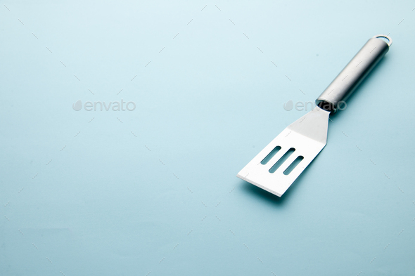 Front view of kitchen stainless spatula lying on the left side pastel ...