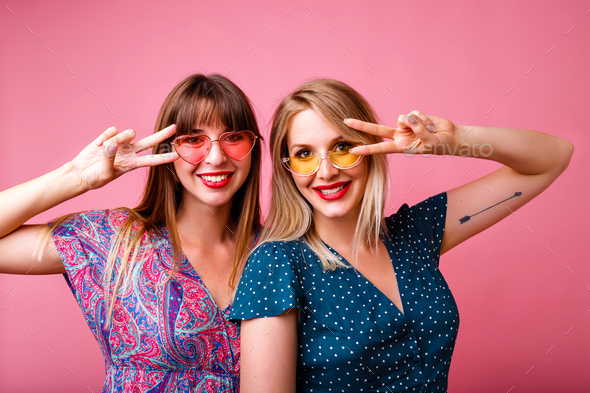 Studio portrait of two positive best friend women having fun at pink ...