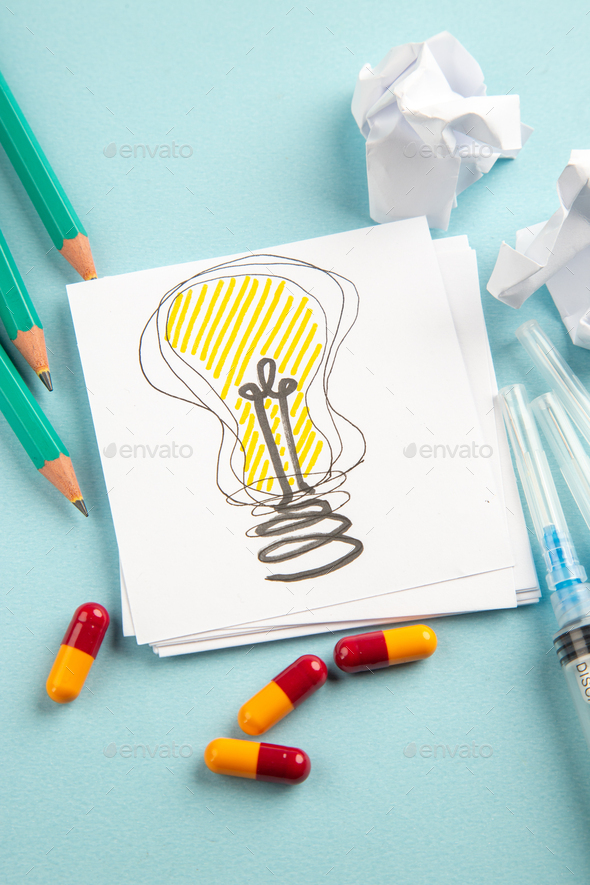 front view lightbulb drawing with pencils pills and injections on blue ...