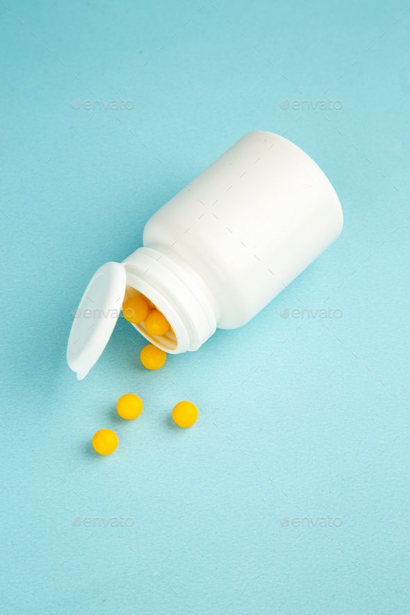 top view little pill can with yellow vitamine pills on blue background ...