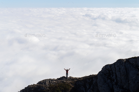 Man standing above clouds in the mountains Stock Photo by olegbreslavtsev