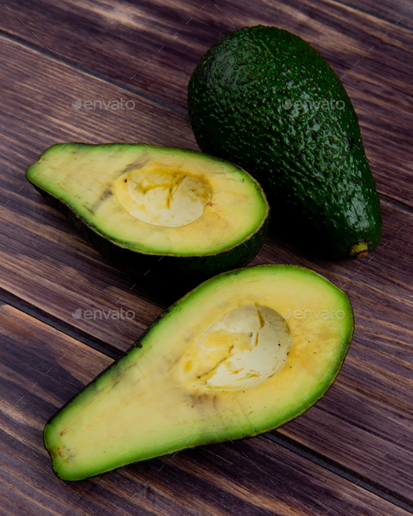 side view of whole and half cut avocados on wooden background Stock ...