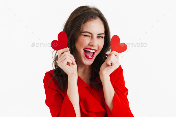 Cheerful beautiful girl winking while making fun with paper hearts ...