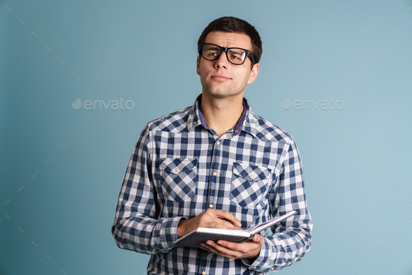 Handsome smart young man writing notes Stock Photo by vadymvdrobot