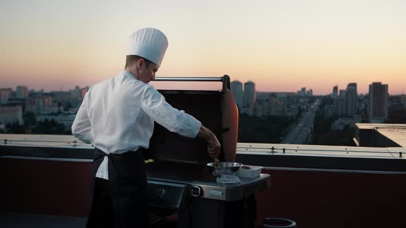 A professional Chef prepares a barbecue on the rooftop of a skyscraper ...