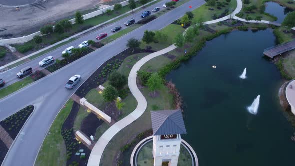 Flying over neighborhood entrance tower and lake towards community ...