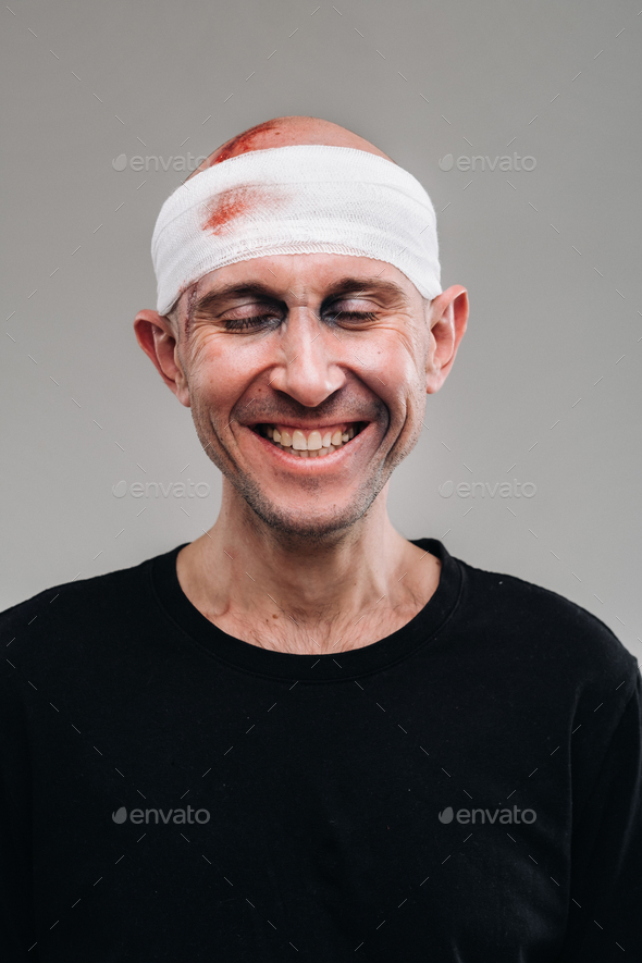 Against a gray background stands a battered and battered man in a black ...