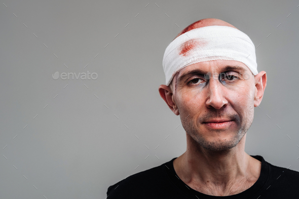 Against a gray background stands a battered and battered man in a black ...