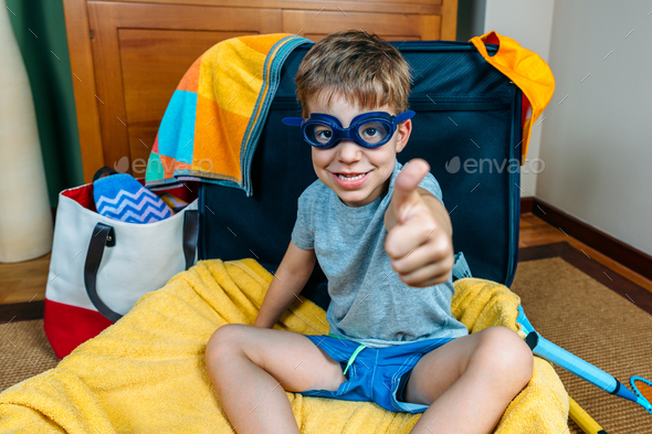 Funny boy smiling sitting inside a suitcase Stock Photo by davidpereiras