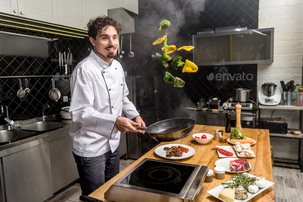 smiling chef tossing up frying bell peppers with frying pan Stock Photo ...