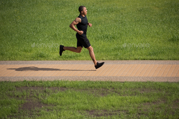 side view of athletic young african american sportsman running in park ...