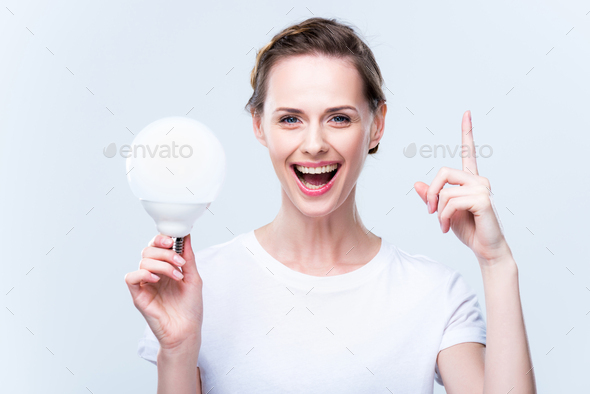 beautiful woman pointing up and holding light bulb, isolated on white ...