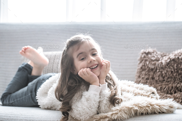 happy little girl lying on the couch, beautiful smile Stock Photo by ...