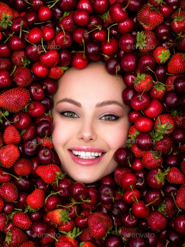 Young, smiling girl with bright makeup and a berry background. Stock ...