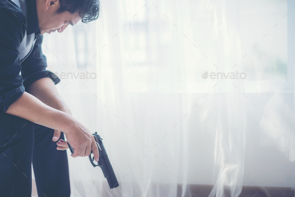 business gangster saying a prayer with his gun Stock Photo by ckstockphoto
