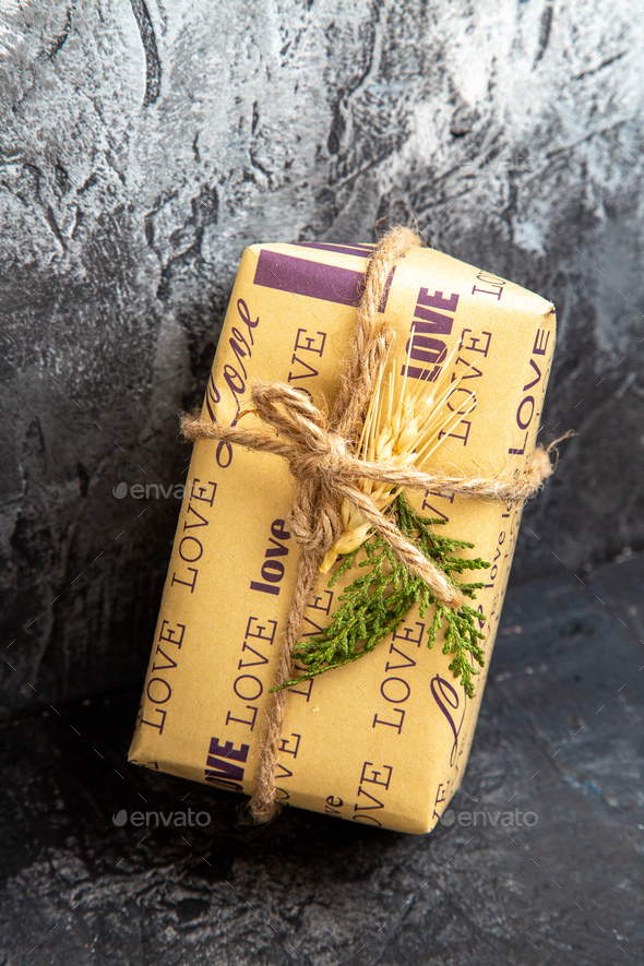 Vertical view of packed gift standing on wall on dark background Stock ...