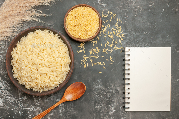 Top view of rice meal and uncooked rice with spoon next to notebook on ...