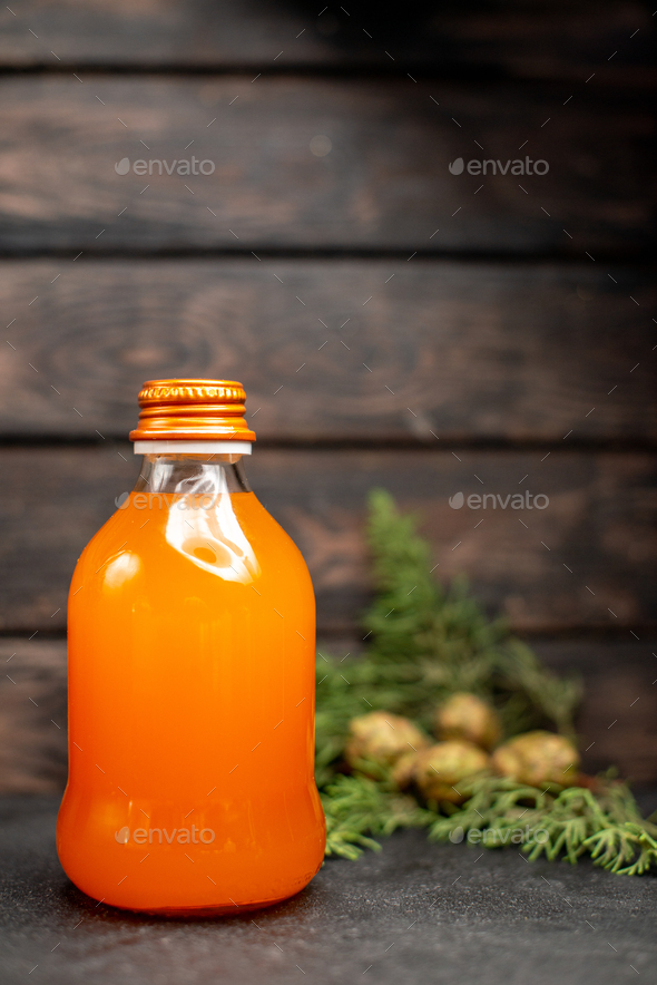 front view orange juice in bottle pine tree branches on brown isolated ...