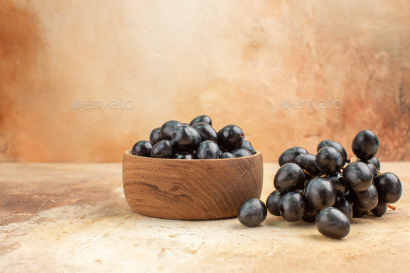 Front close view of black fresh grapes in small pots and on table on ...