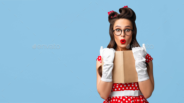 Shocked pinup woman reading book with eyes wide open on blue studio ...