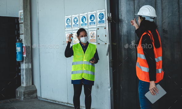 supervisor measuring temperature of workers with thermometer at ...