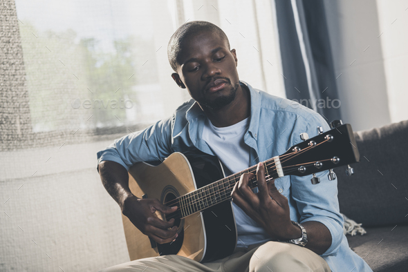 African american man playing acoustic guitar at home Stock Photo by ...