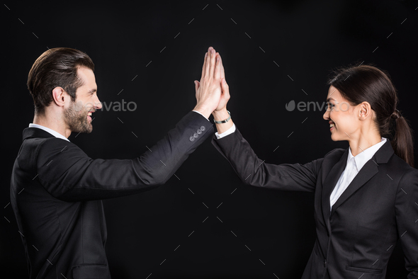 Young smiling businesspeople giving high five isolated on black Stock ...