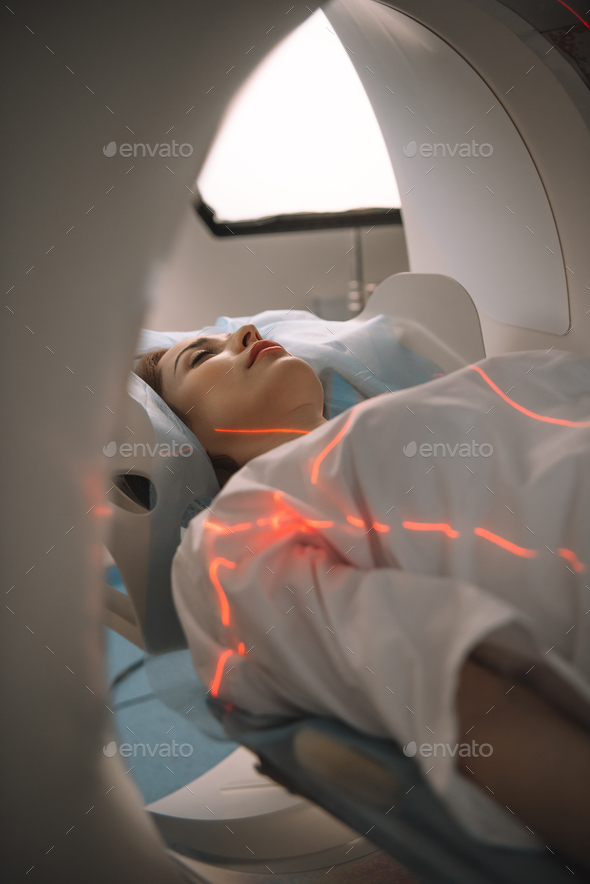 young woman lying on ct scanner bed during tomography diagnostics in ...