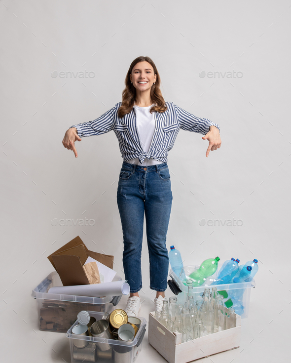 Young lady sorting waste, pointing at containers with different kind of ...