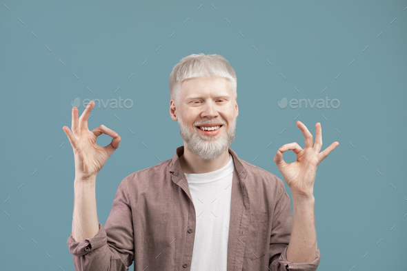 Happy blond man with unusual albino appearance meditating, keeping his ...