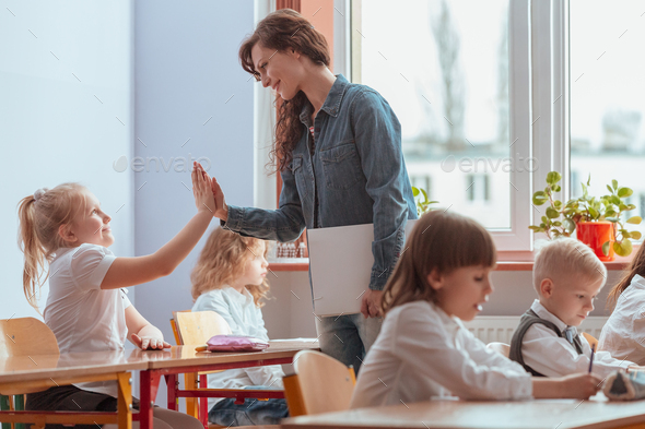 Young teacher gives a high five to the student Stock Photo by bialasiewicz