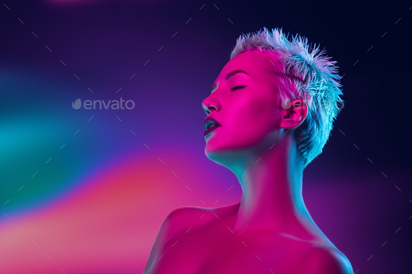 Portrait of female fashion model in neon light on dark studio ...