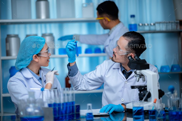 group of laboratory assistants checking blood, using microscope and ...