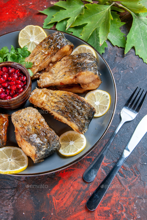 Top view (fried fish) on the blue plate with lemon slices pomegranate ...