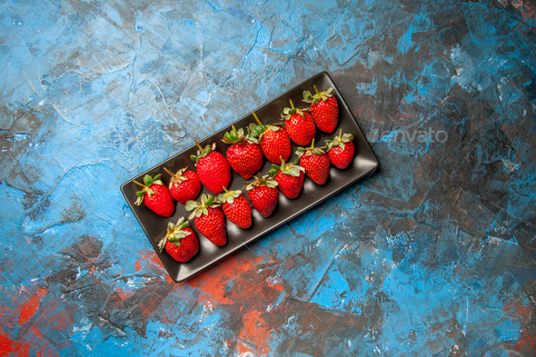 top view red strawberries inside black pan on a blue background red ...
