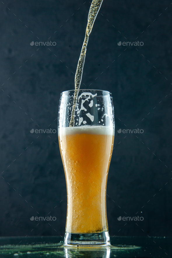 Half-drunk home-brewed beer in a glass pouring from a bottle standing ...