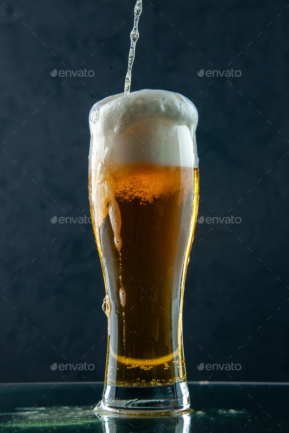 Home-brewed beer overflowing and pouring from a glass with foam ...