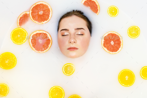 Pretty woman in bath with orange lemon. Stock Photo by maksimovata