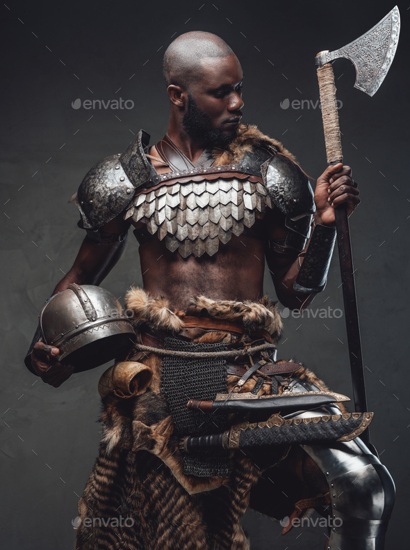 Wild barbaric person with black skin wielding an axe posing in dark ...