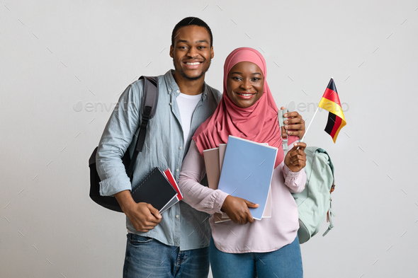 Cheerful african american muslim students couple holding german flag ...
