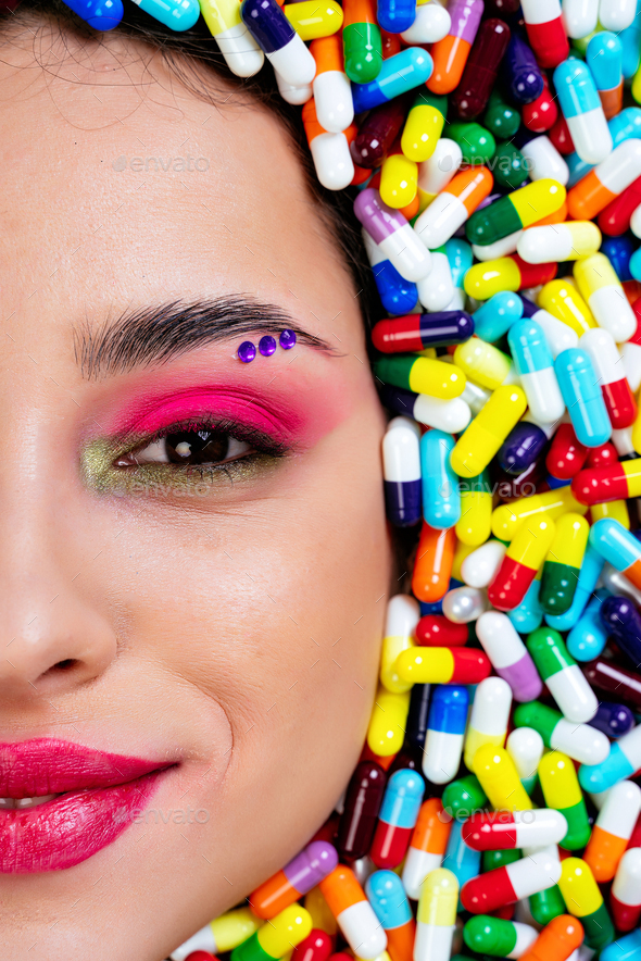 Artistic image of a beautiful woman sunk inside colored pills and ...