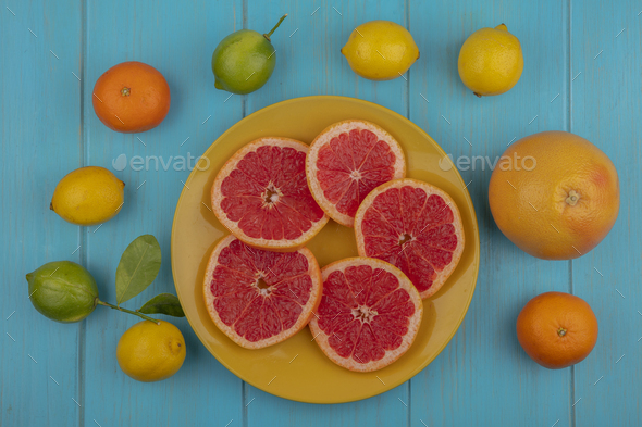 top view grapefruit wedges on yellow plate with lime and lemons on ...