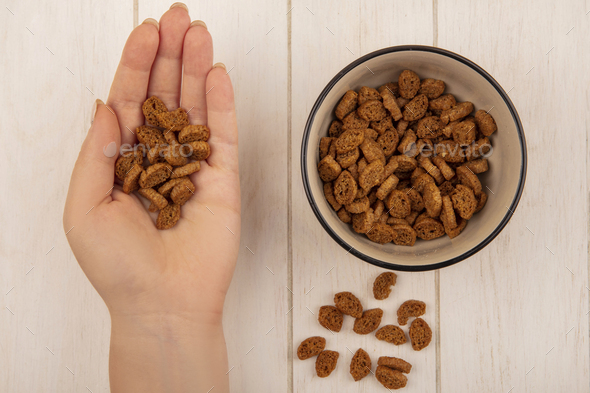 top view of female hand holding small rye rusks with a bowl of rye ...