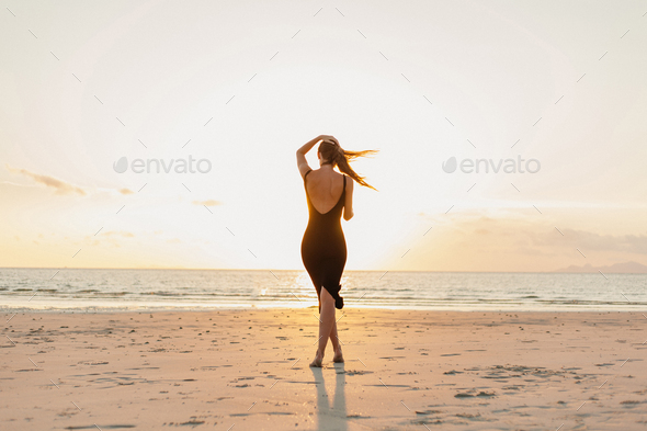 back view of girl posing in dress on sandy beach during beautiful ...