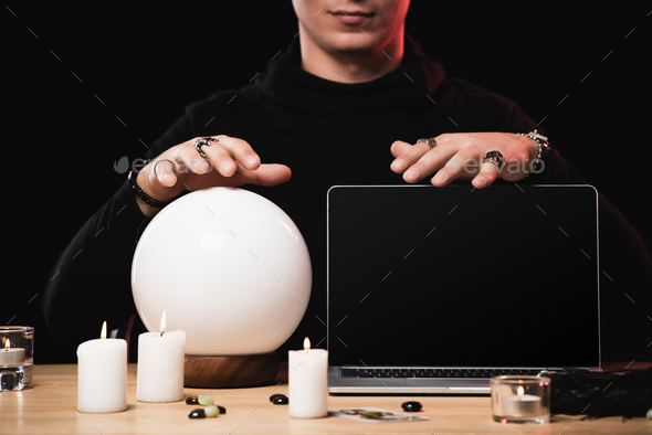 cropped view of oracle near laptop with blank screen isolated on black ...