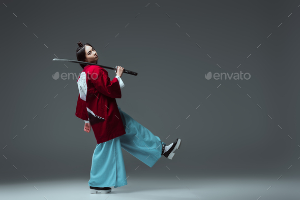 side view of samurai in kimono walking with katana and looking at ...