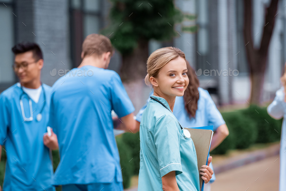 smiling medical student looking at camera on street near medical ...